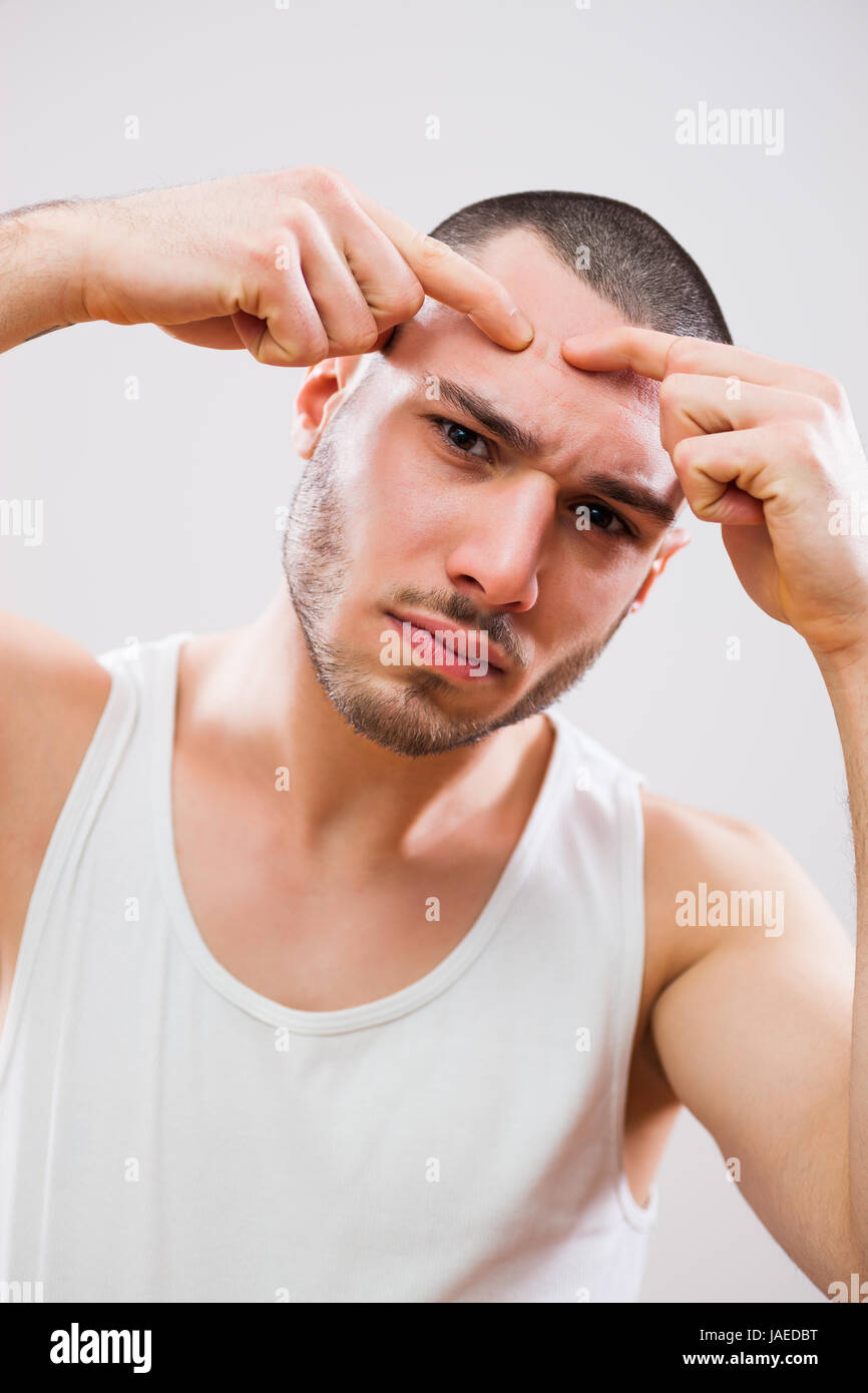 Young man is squeezing pimple on his forehead Stock Photo - Alamy