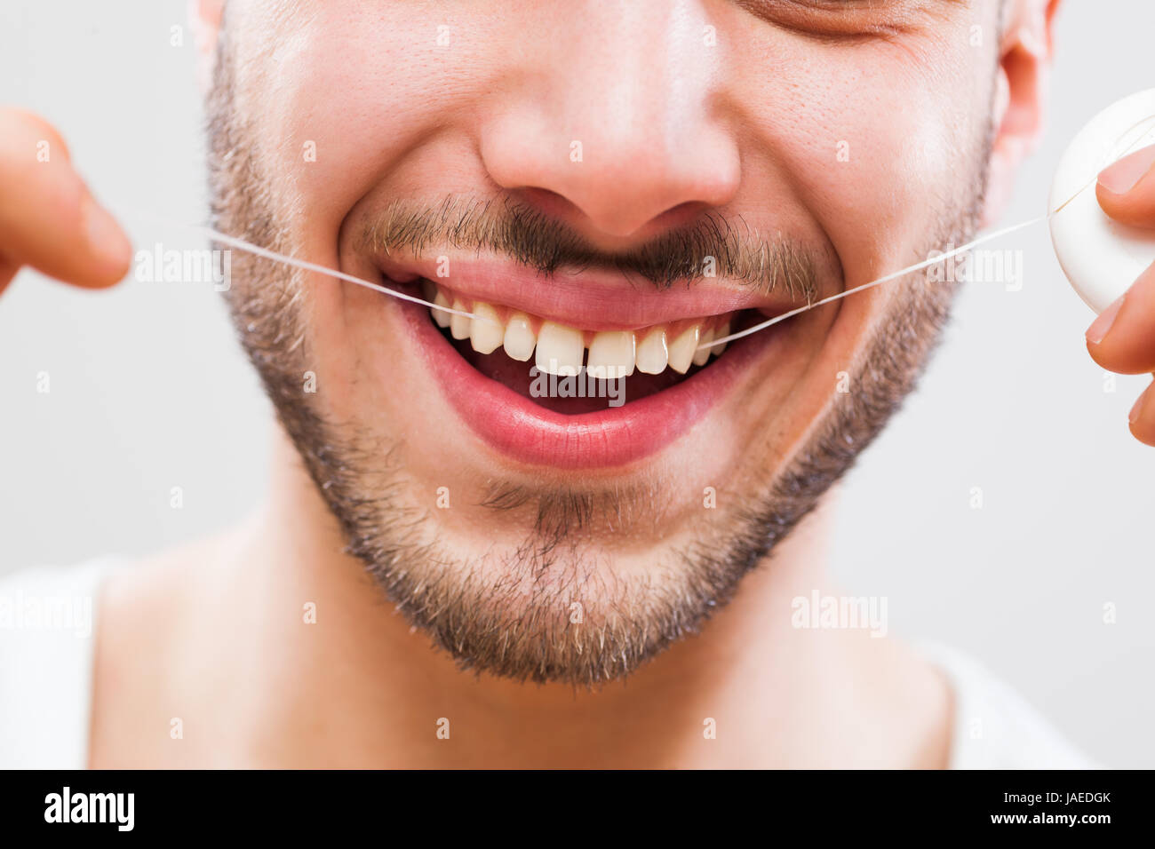 Young man is using dental floss to clean his teeth Stock Photo - Alamy