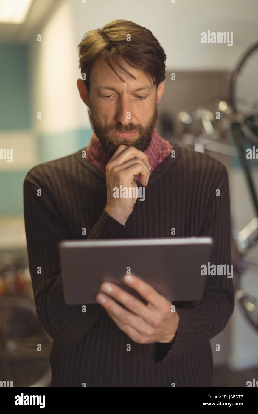 Thoughtful employee using digital tablet at bicycle workshop Stock ...
