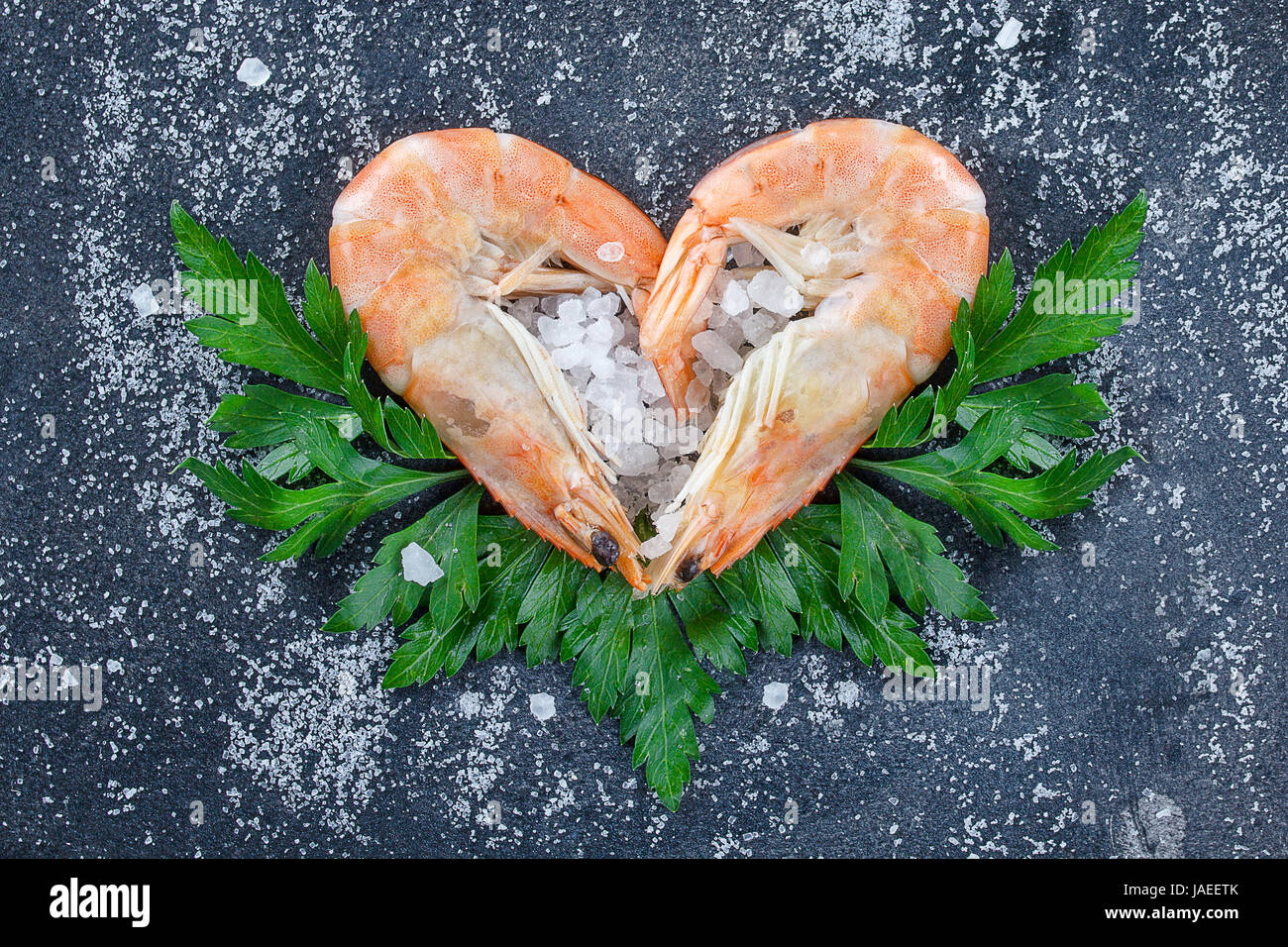 Raw prawns, shrimps with hearts with condiments on a stone background ...
