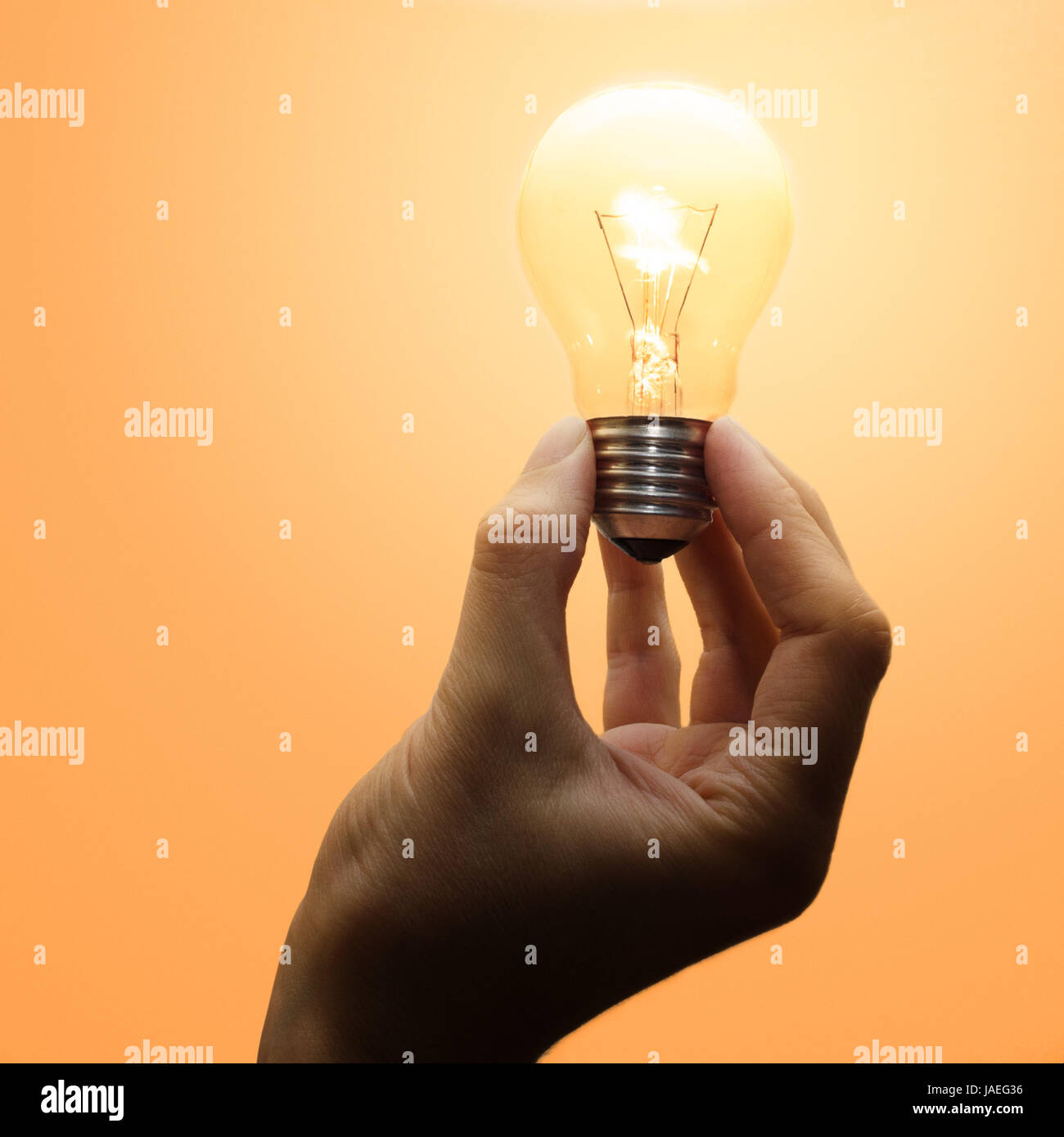 A luminescent light bulb hold by a human hand. Warm light Stock Photo ...