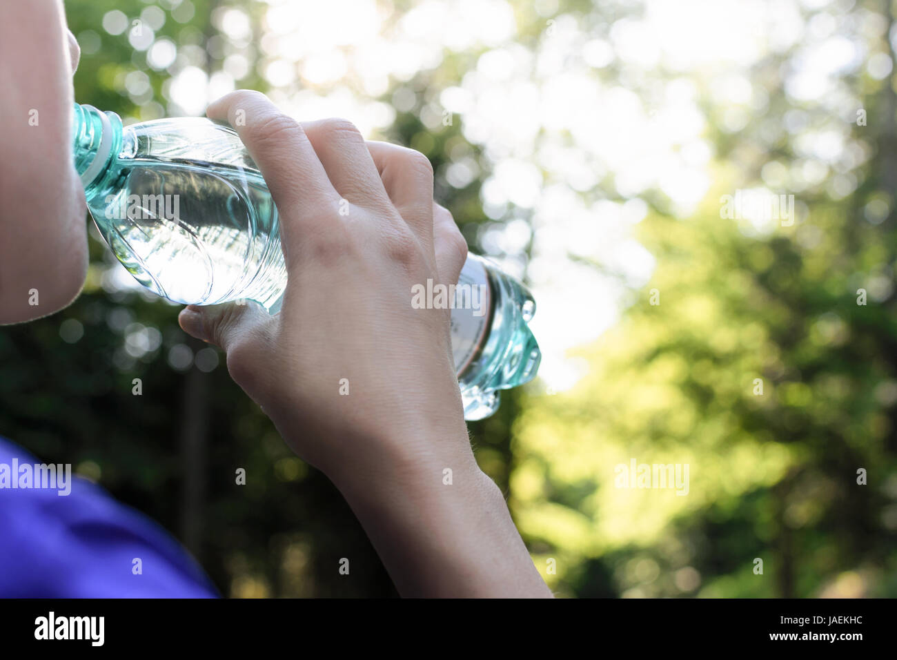 Woman drinking mineral water and resting while jogging in the park ...
