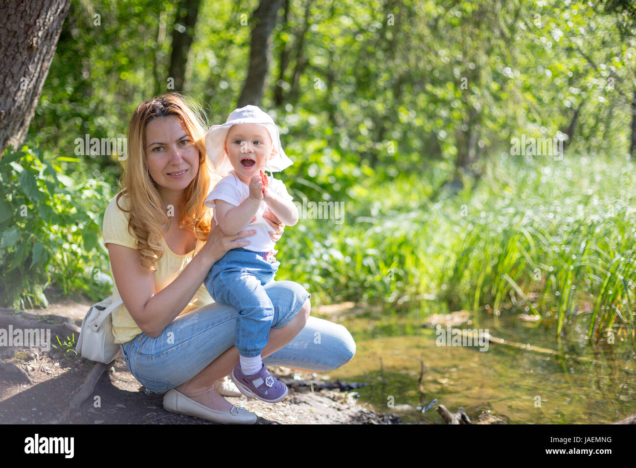 Mother and happy baby girl on the shore of a lake Stock Photo - Alamy