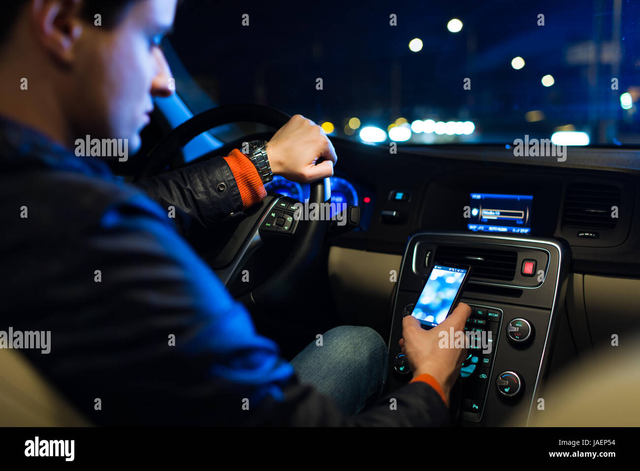 Driving a car at night -man driving his modern car at night in a city ...