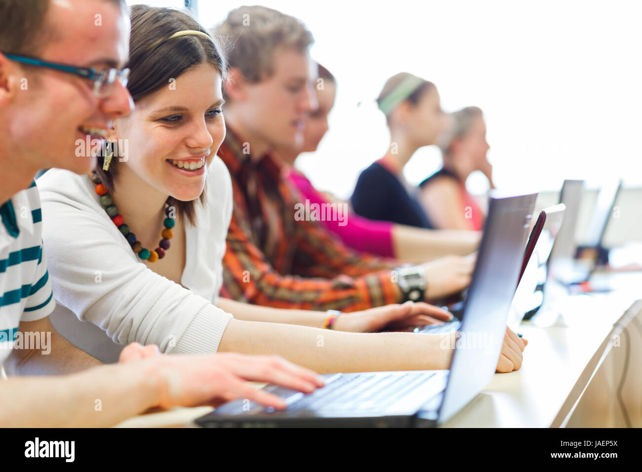College students sitting in a classroom, using laptop computers during ...