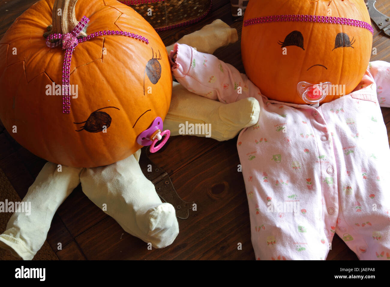 Two pumpkins dressed up as princess babies with pacifiers, seen from ...