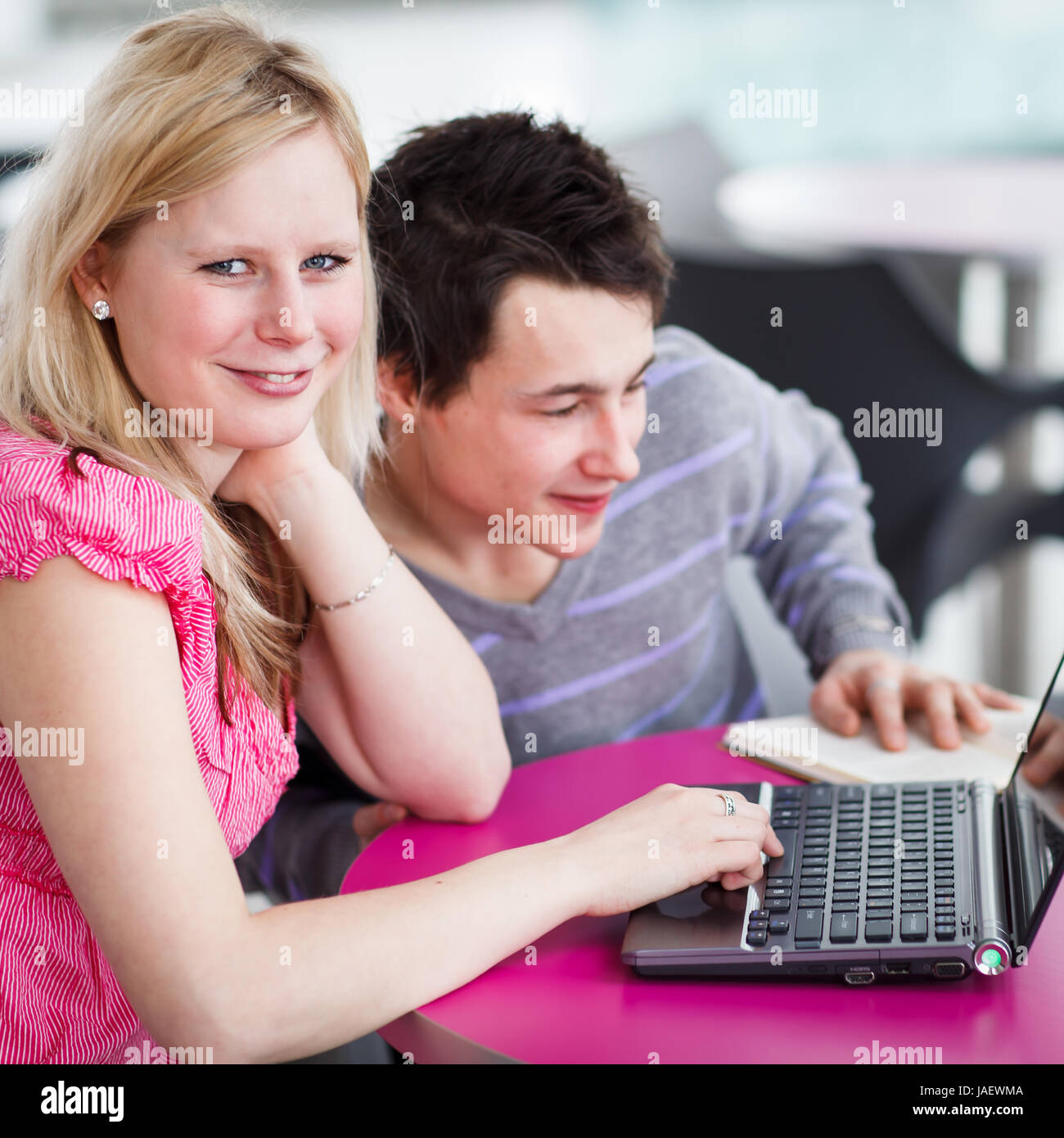 Two college students having fun studying together, using a laptop ...