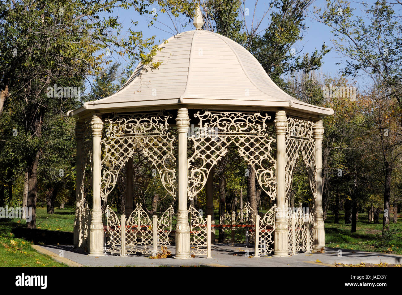 Beautiful gazebo in autumn park surrounded by trees and green grass ...