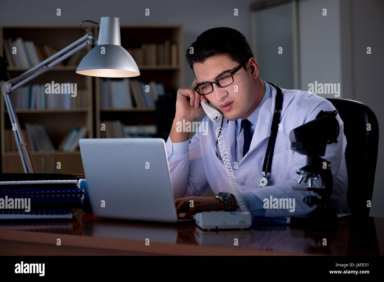 Young doctor working late in the office Stock Photo - Alamy