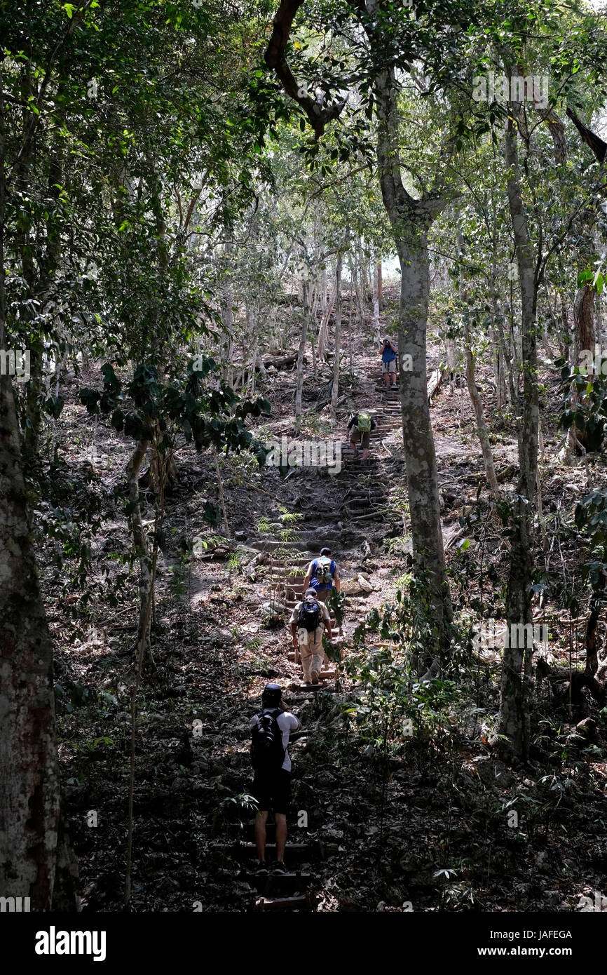 Hikers climbing an ancient triadic pyramid of the Preclassic Maya ...