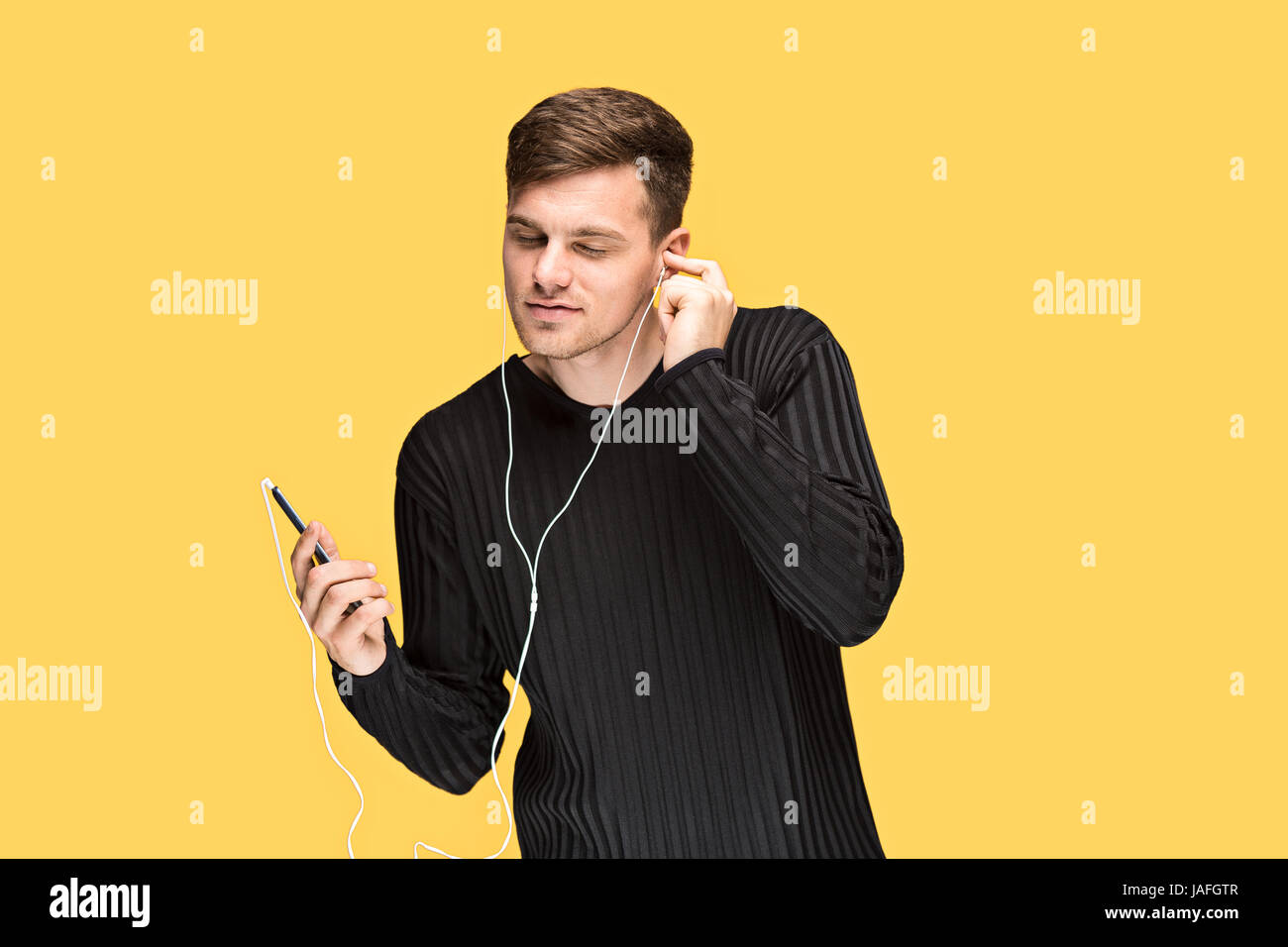 The handsome young man standing and listening music Stock Photo - Alamy