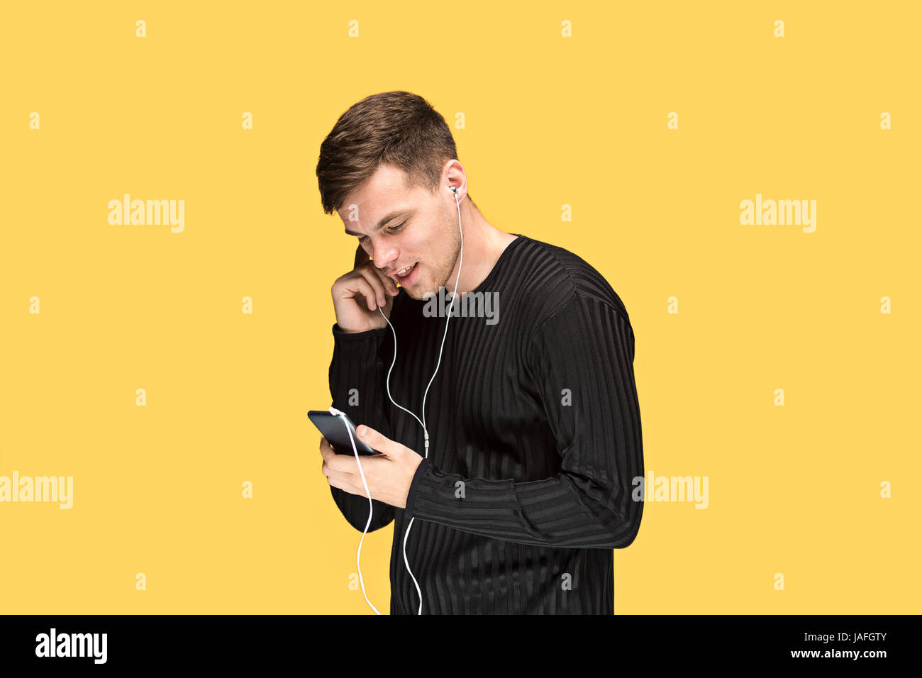 The handsome young man standing and listening music Stock Photo - Alamy
