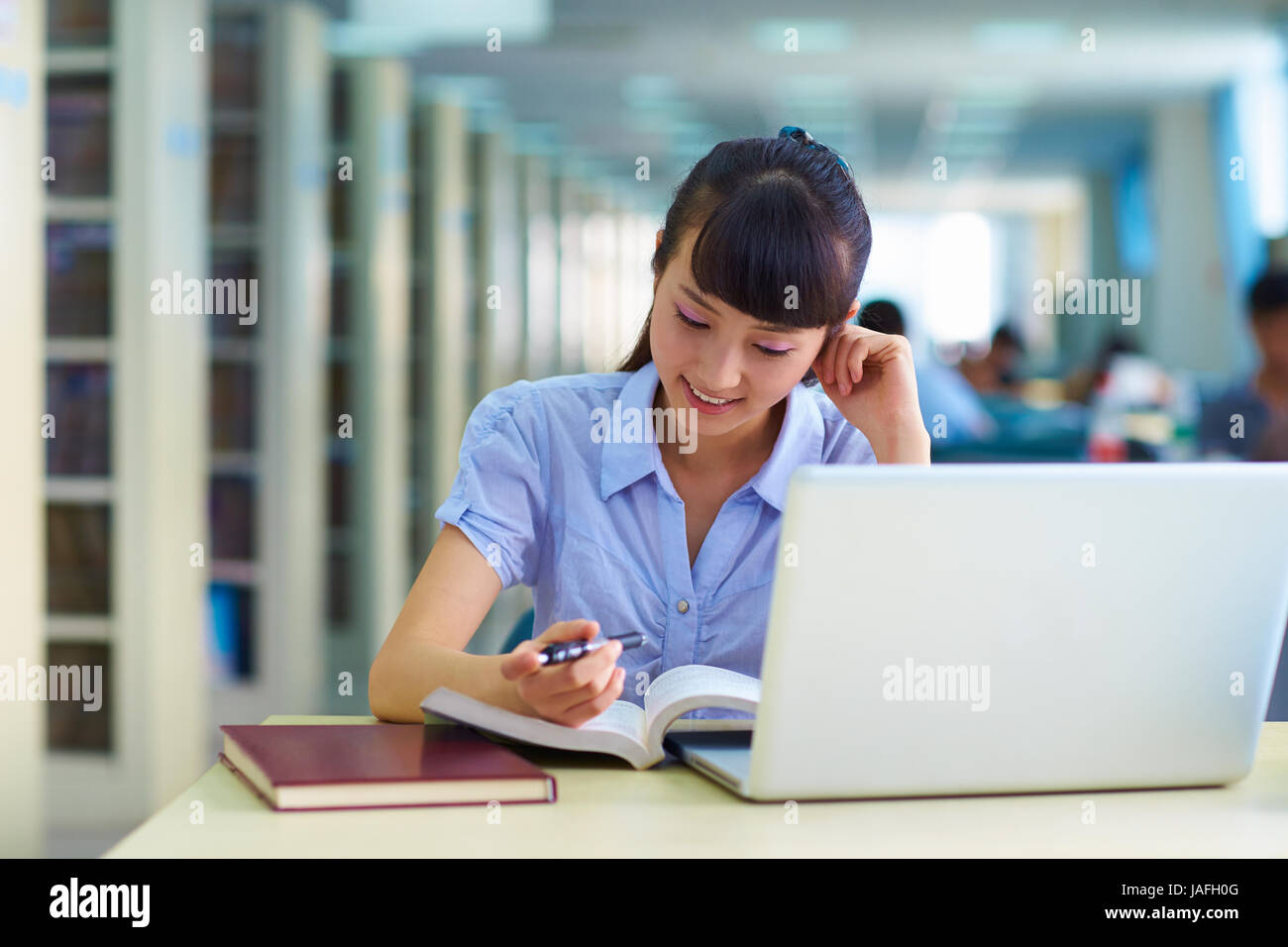 one pretty young Asian or Chinese college student study in the library ...