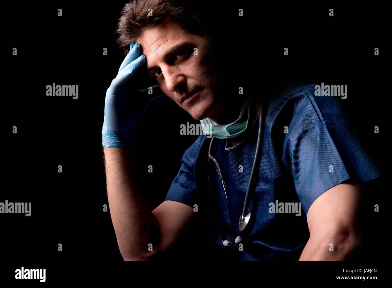 Tired doctor in uniform isolated against a black background Stock Photo ...