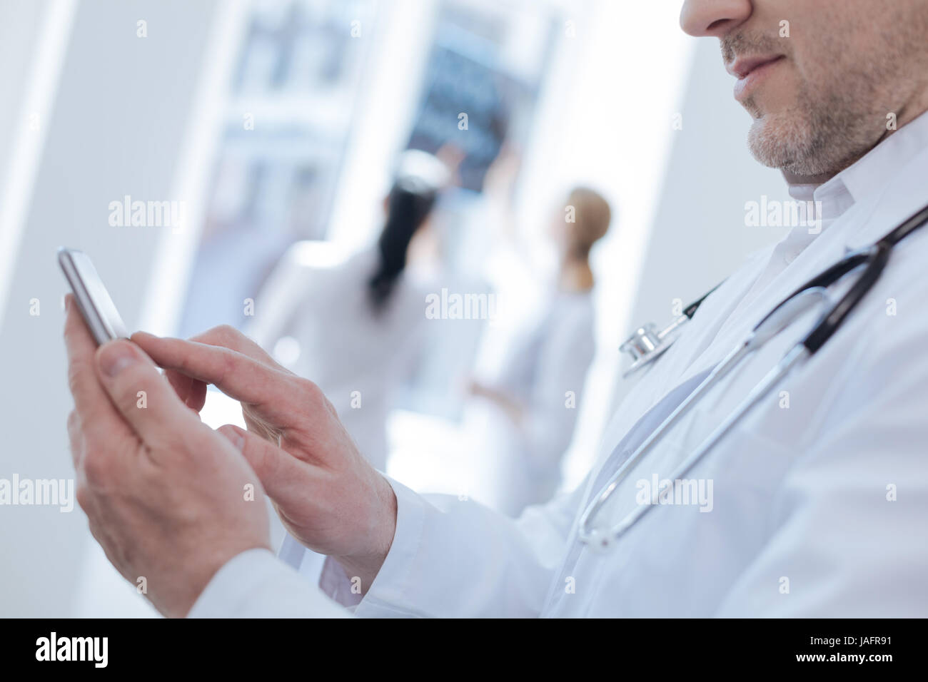 Using digital gadget at work. Handsome positive experienced medic ...