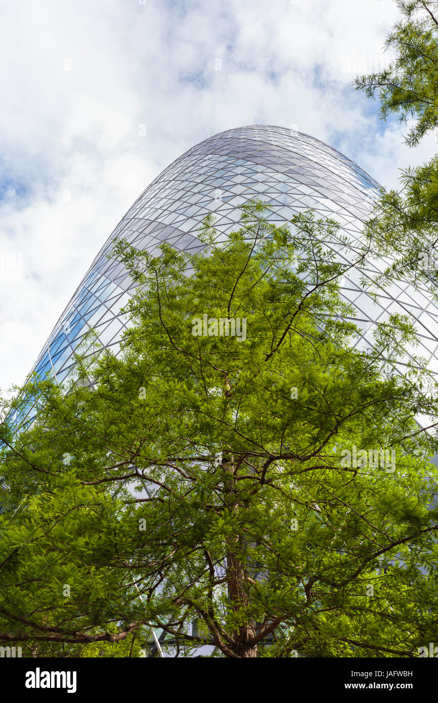 The Gherkin, iconic skyscraper building, from below with trees. City of ...