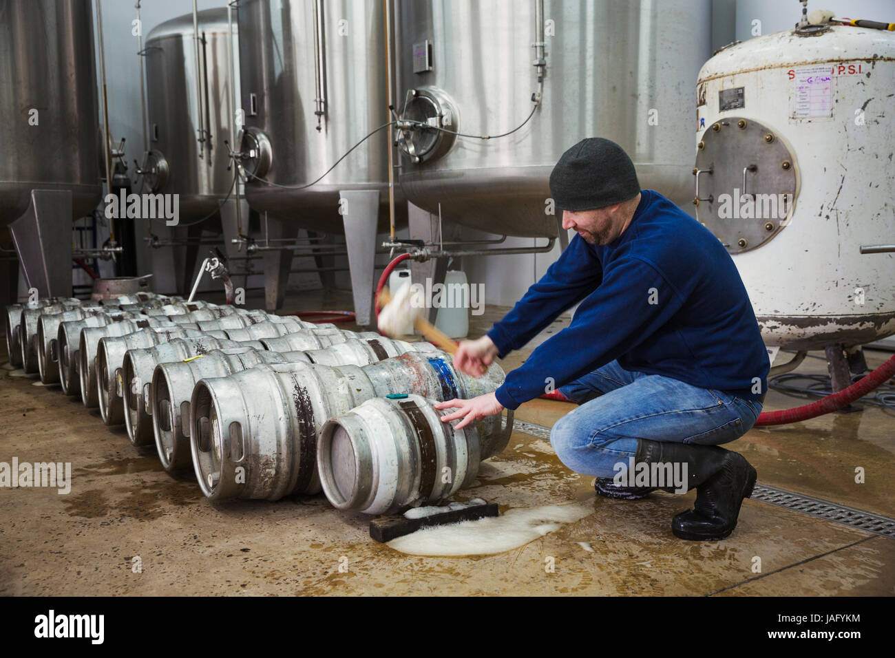 Man kneeling and hammering in a peg into a metal beer keg. Large ...