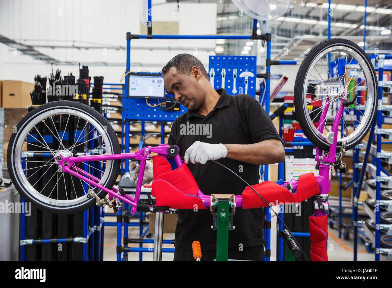 Male skilled factory worker assembling a bicycle in a factory ...