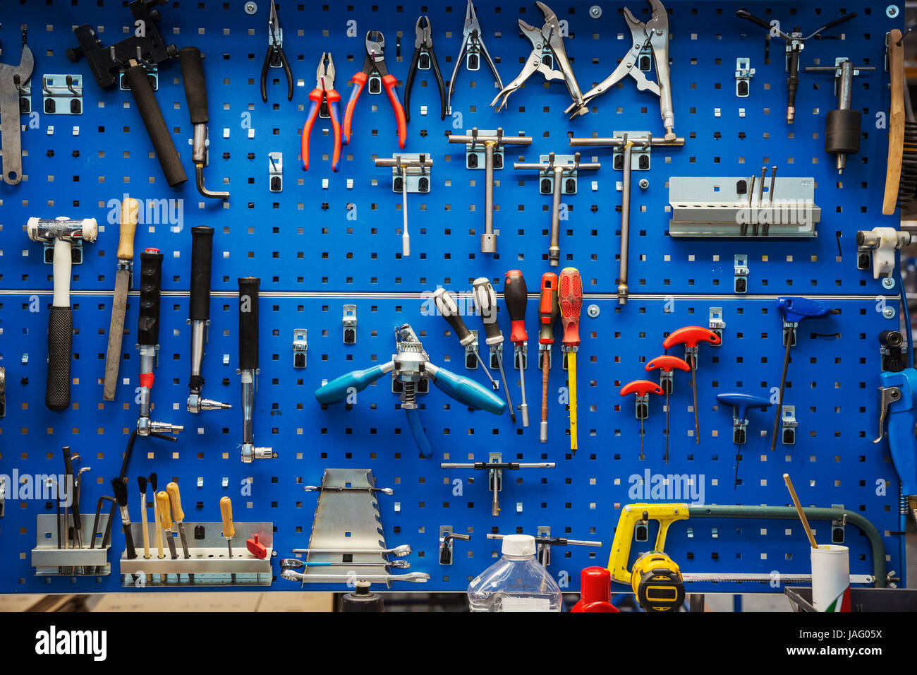 Large selection of hand tools organised and hung up neatly on a blue ...