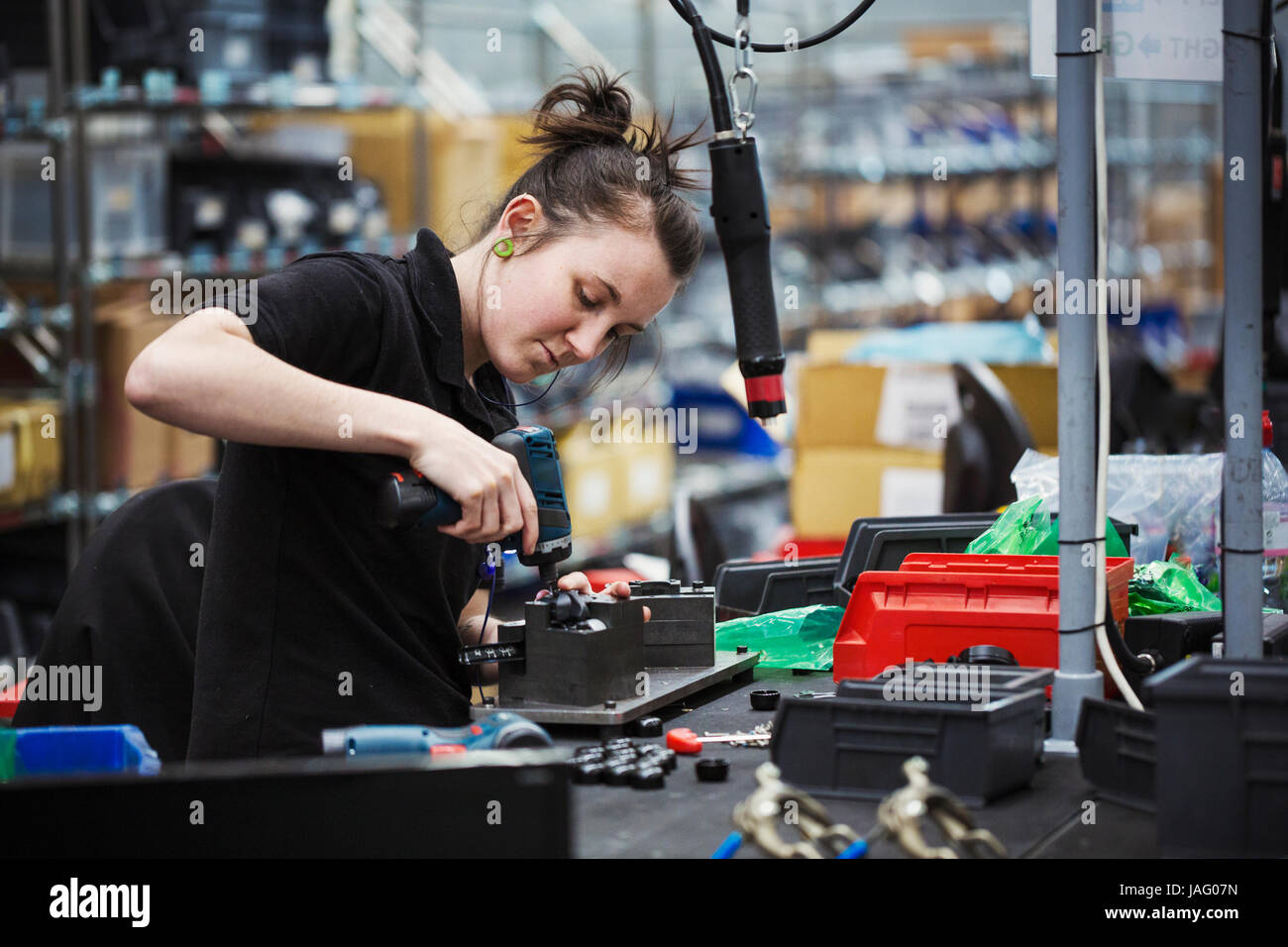 A young woman using a power tool, a skilled factory worker assembling ...