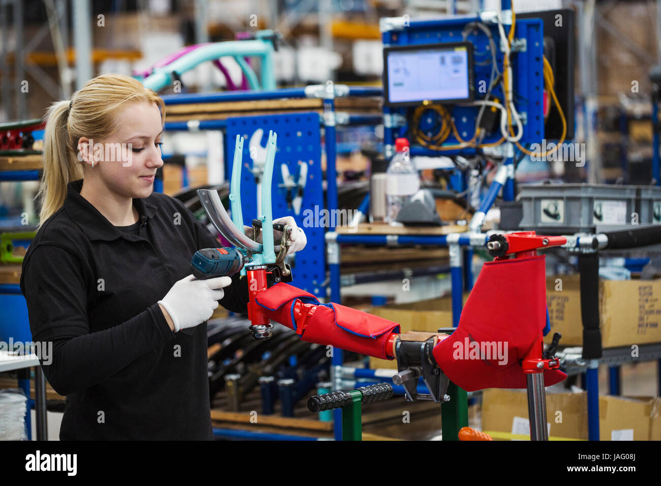 Female skilled factory worker assembling a bicycle handling the brakes ...