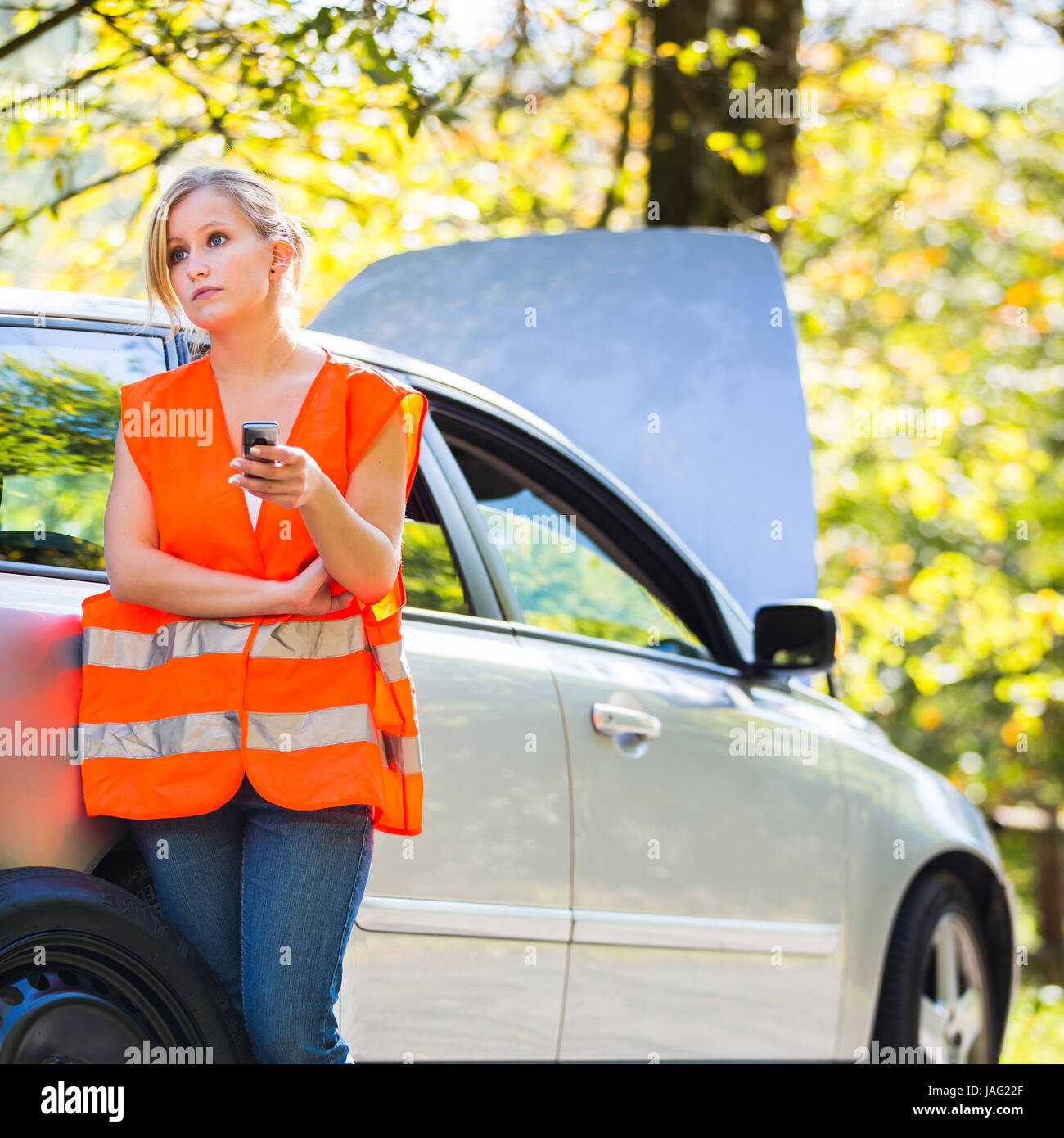 Young female driver wearing a high visibility vest, calling the ...