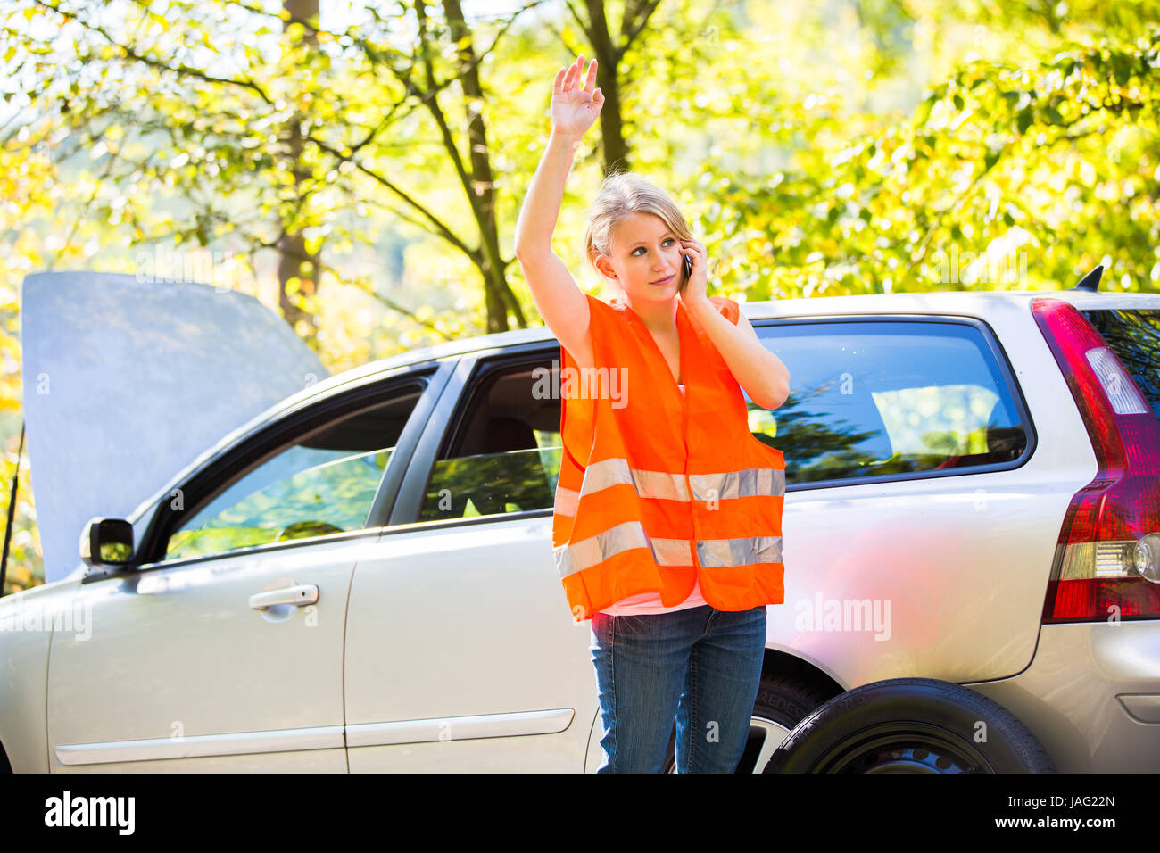 Young female driver wearing a high visibility vest, calling the ...