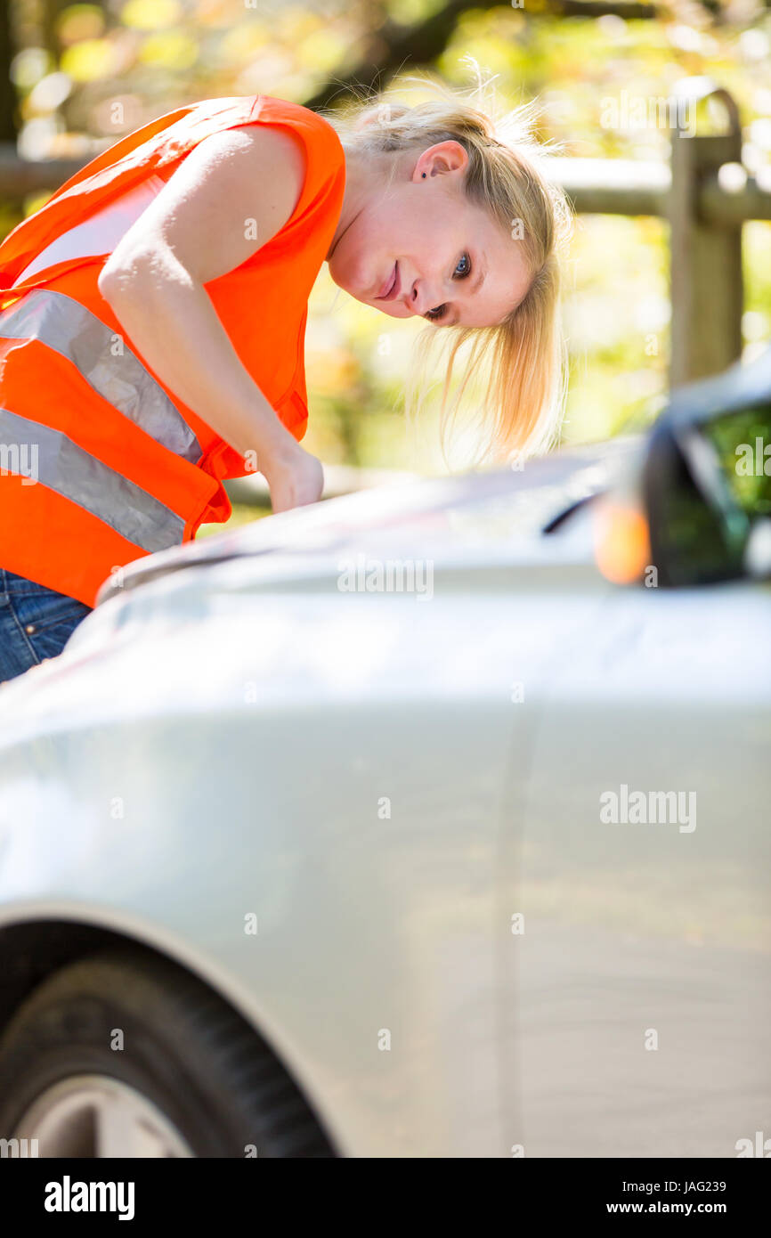 Young female driver wearing a high visibility vest on the roadside ...