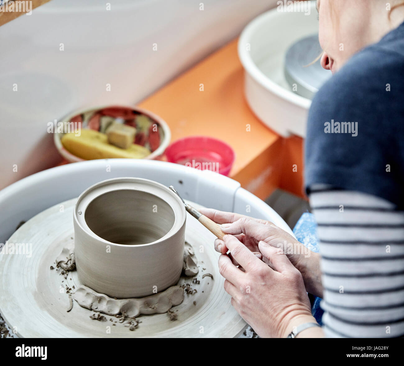 A person using a pottery wheel finishing and shaving curls of clay off ...