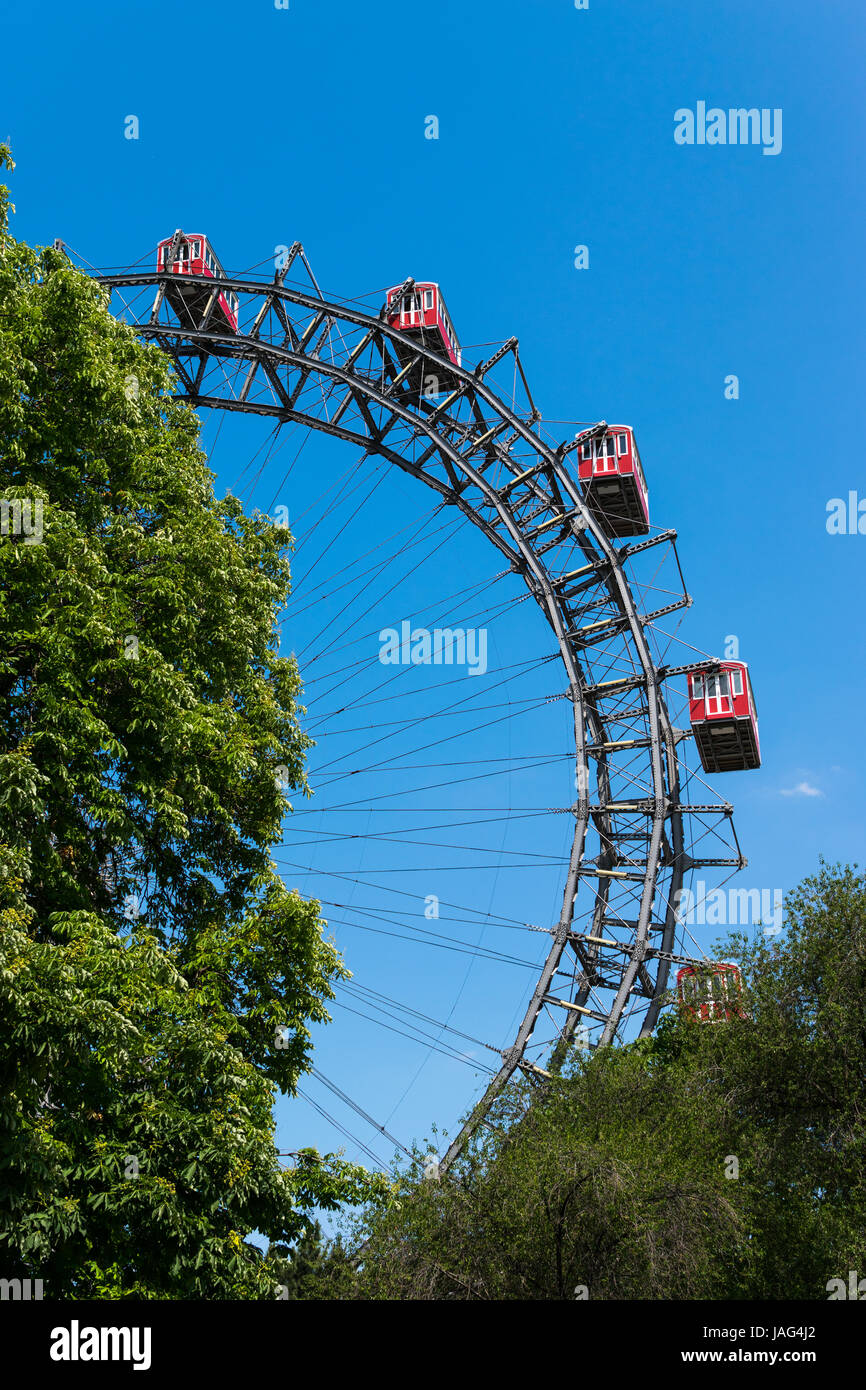 Impressive red Ferris wheel on clear blue sky with trees in the ...