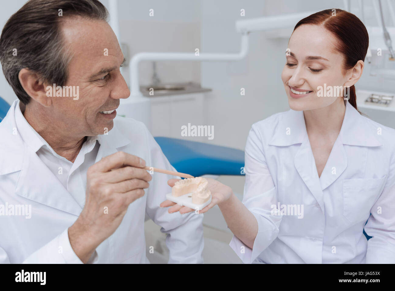 Give explanations. Very glad intern wearing white smock and keeping ...