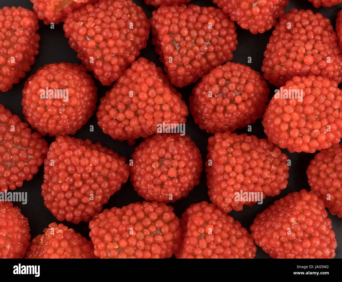 A very close view of raspberry shaped candies on a black background ...