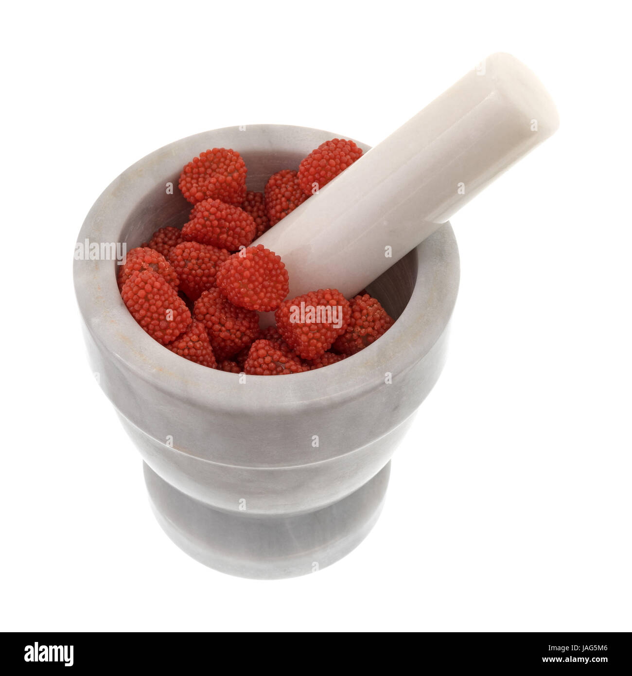 Several raspberry shaped candies in a marble mortar and pestle isolated ...