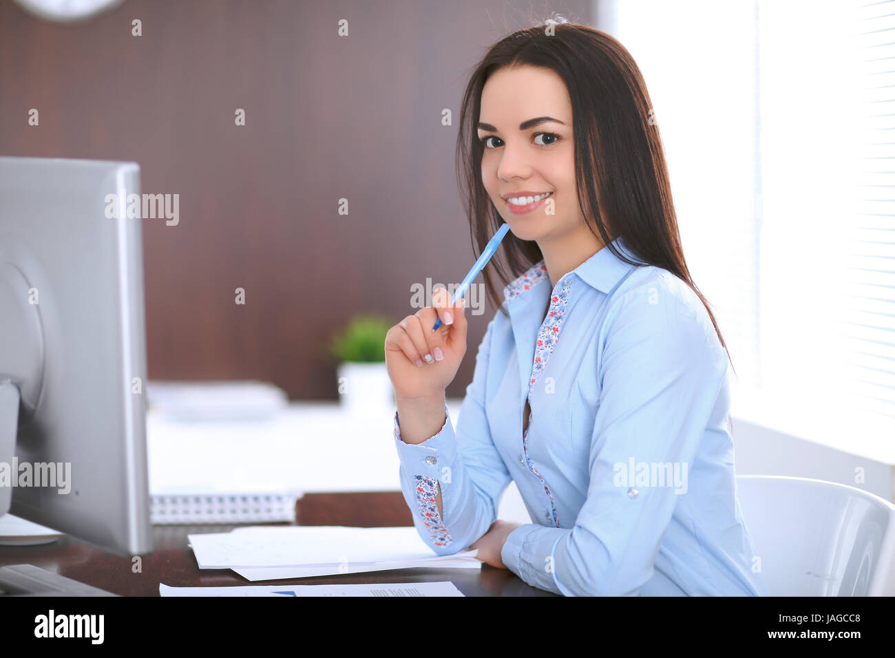 Young business woman sitting a at the table in office Stock Photo - Alamy