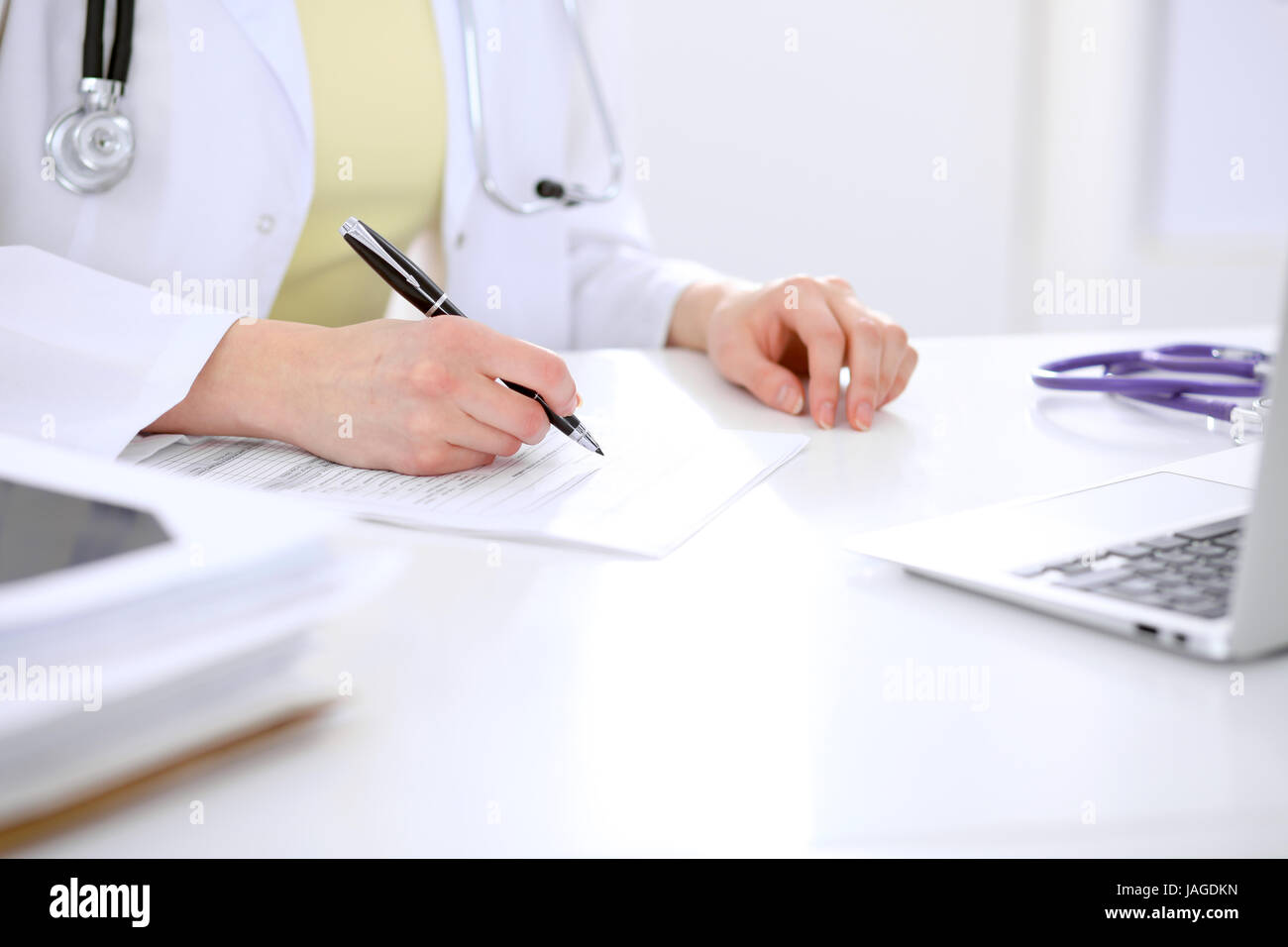 Close-up of a female doctor filling out application form , sitting at ...