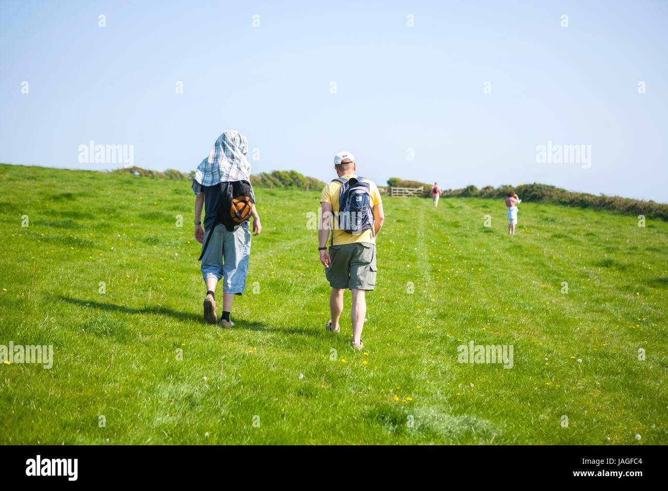 two men walking along green country paths enjoying outdoor hiking and ...