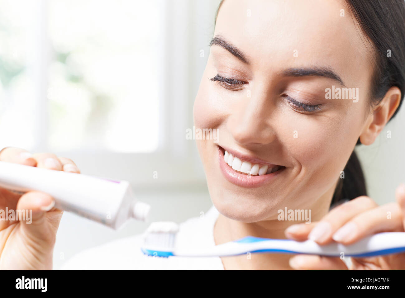 Woman Squeezing Toothpaste Onto Tootbrush In Bathroom Stock Photo - Alamy