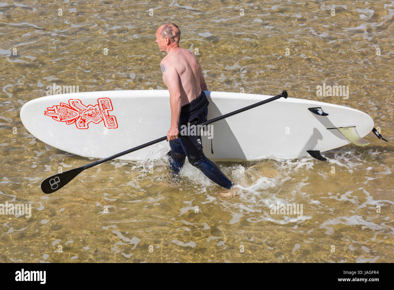 Man carrying paddleboard at bournemouth beach hi-res stock photography ...