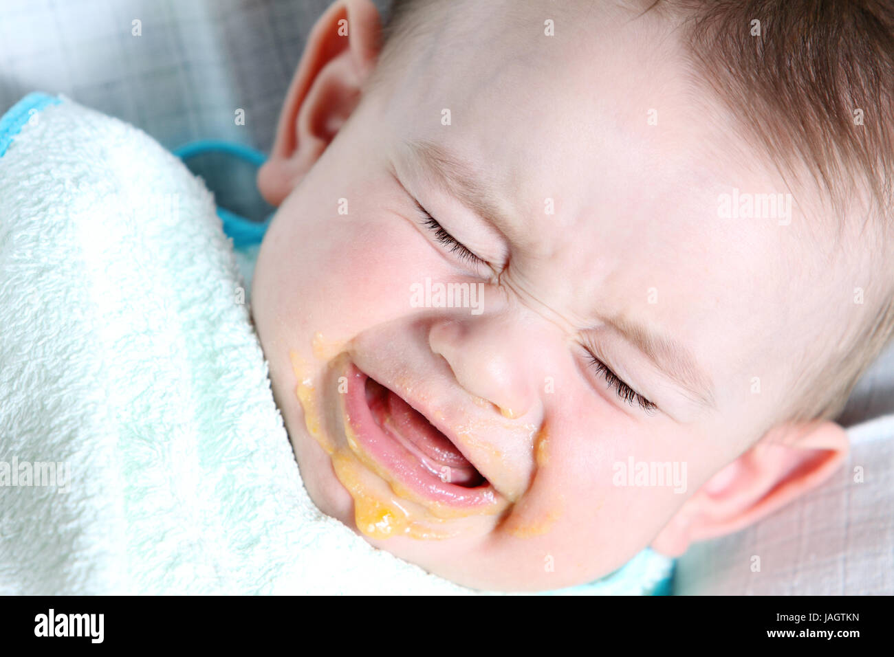 Crying baby boy eating vegetable mash Stock Photo - Alamy