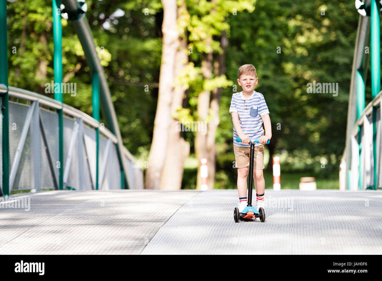 Boy riding his scooter in the local park. Sunny summer Stock Photo - Alamy