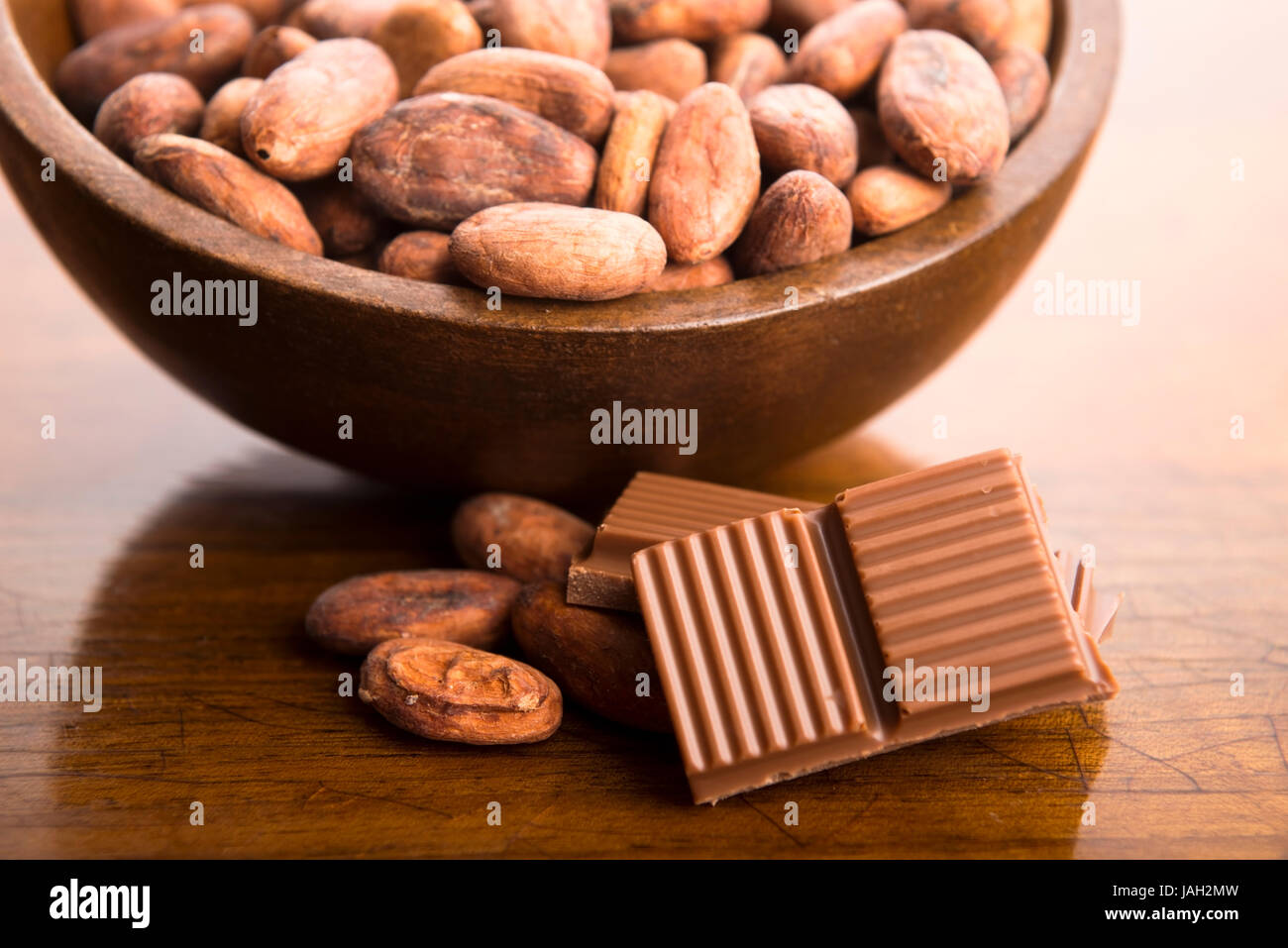 Cacao beans with milk chocolate Stock Photo - Alamy