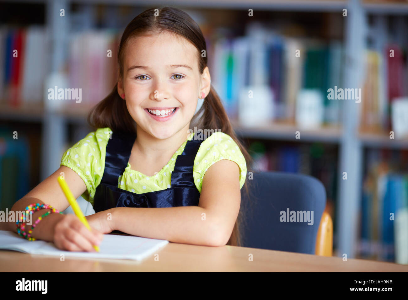 Portrait of a lovely girl sitting in library Stock Photo - Alamy