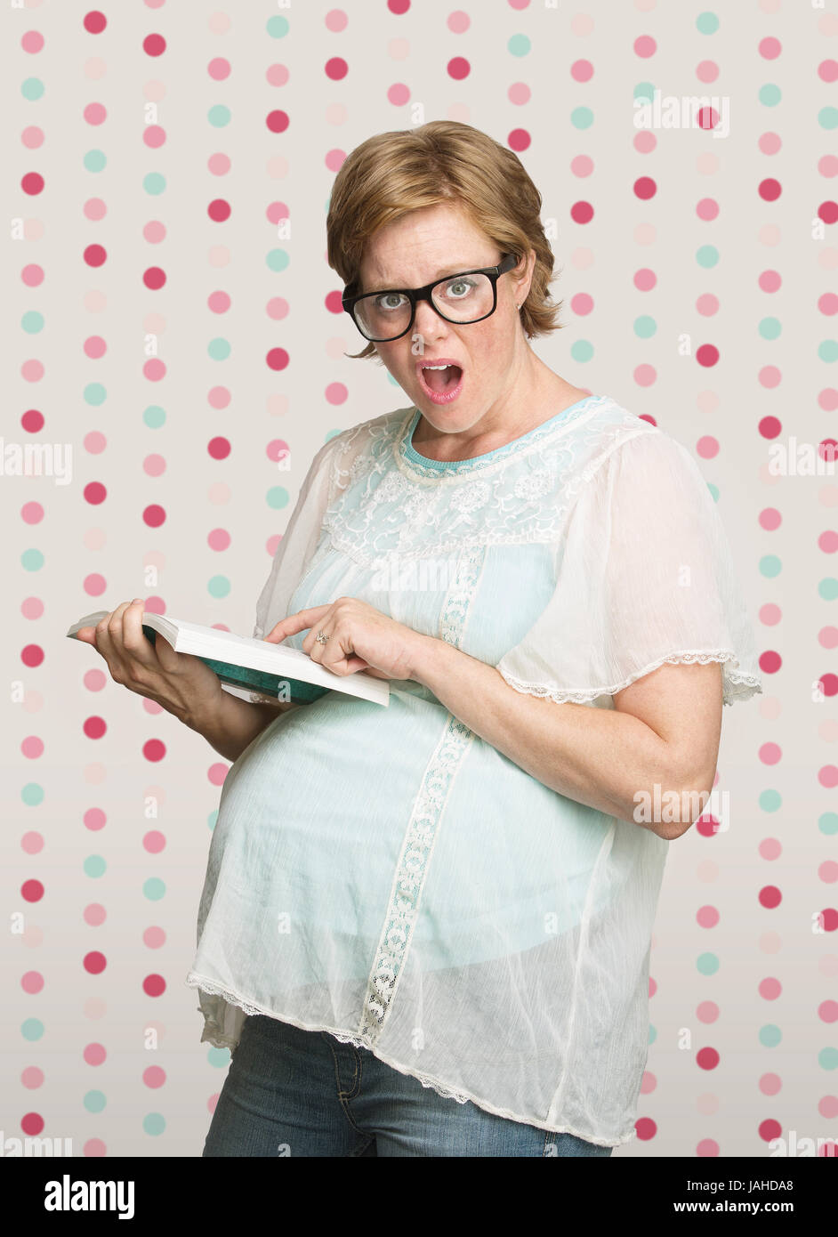 Astonished single pregnant female pointing at a book Stock Photo - Alamy