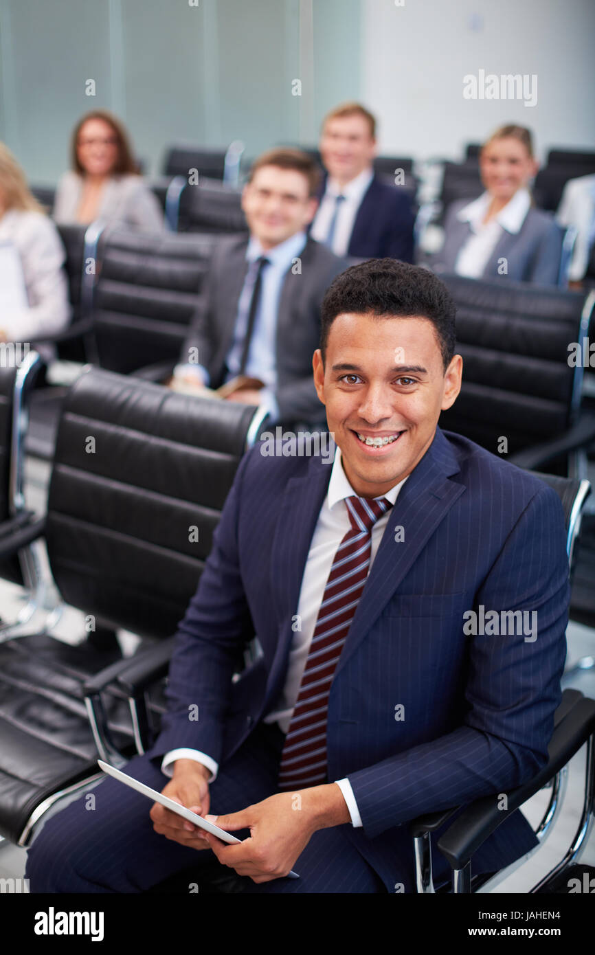 Image of business partners sitting in rows at seminar with smiling man ...