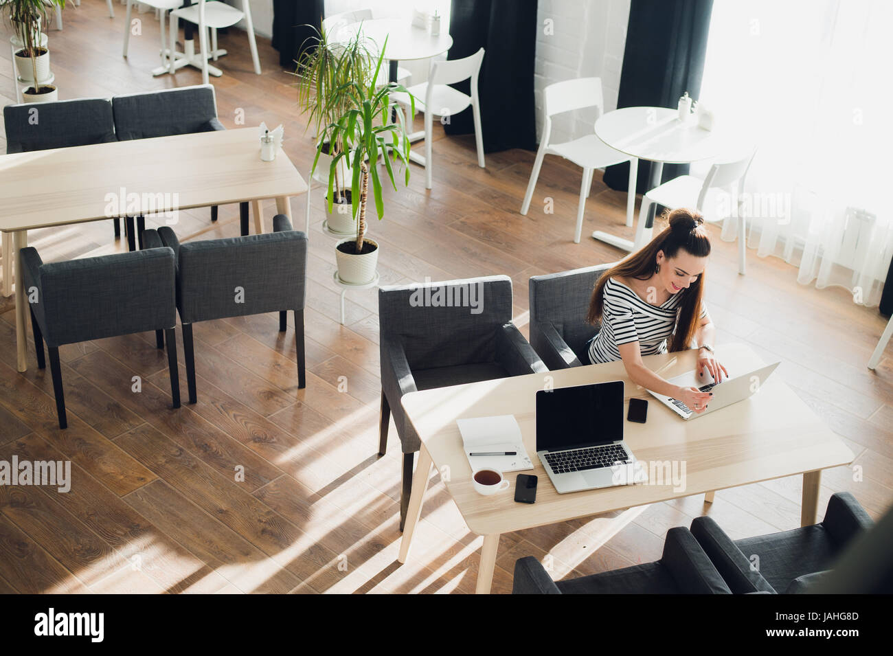 Side view. Young business woman sitting at table and taking notes in ...
