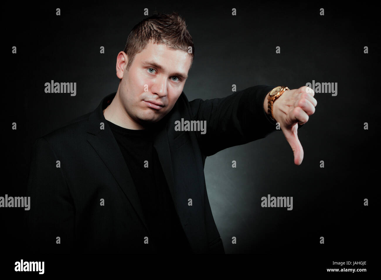 disappointed young man showing thumb down hand sign looking with ...