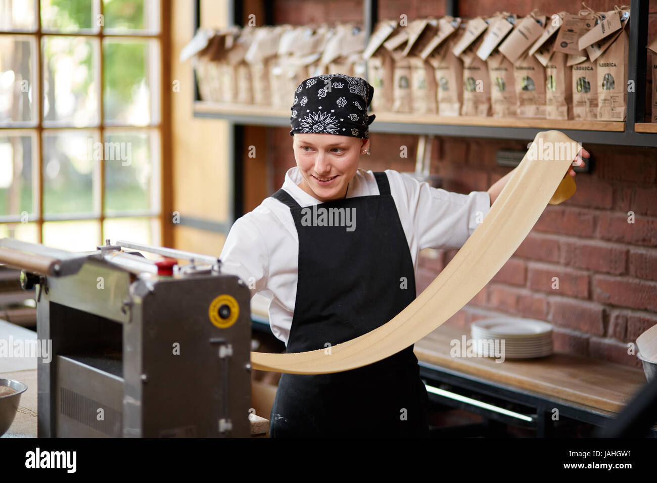 Woman cooks dough on machine for making pasta Stock Photo - Alamy