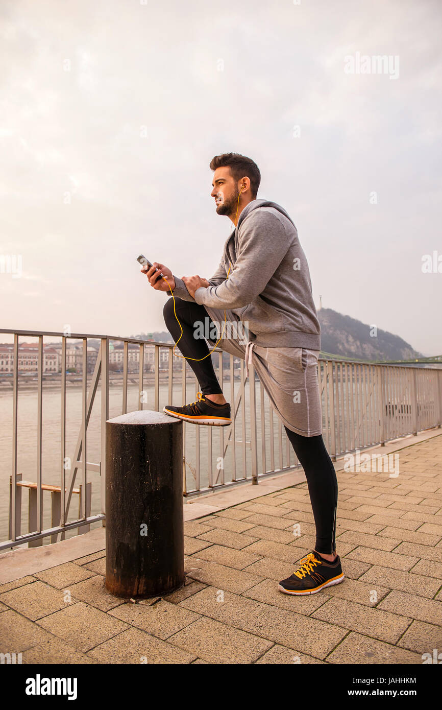 A handsome young man putting his leg up and leaning on it while using ...