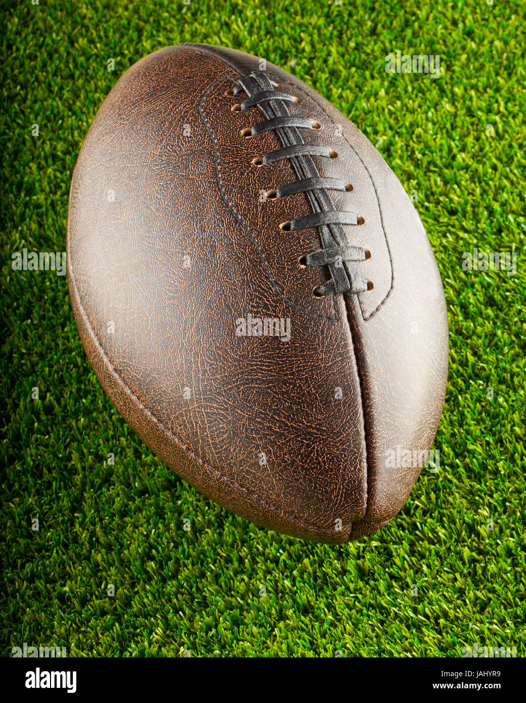 Brown leather football over a background of green grass Stock Photo - Alamy