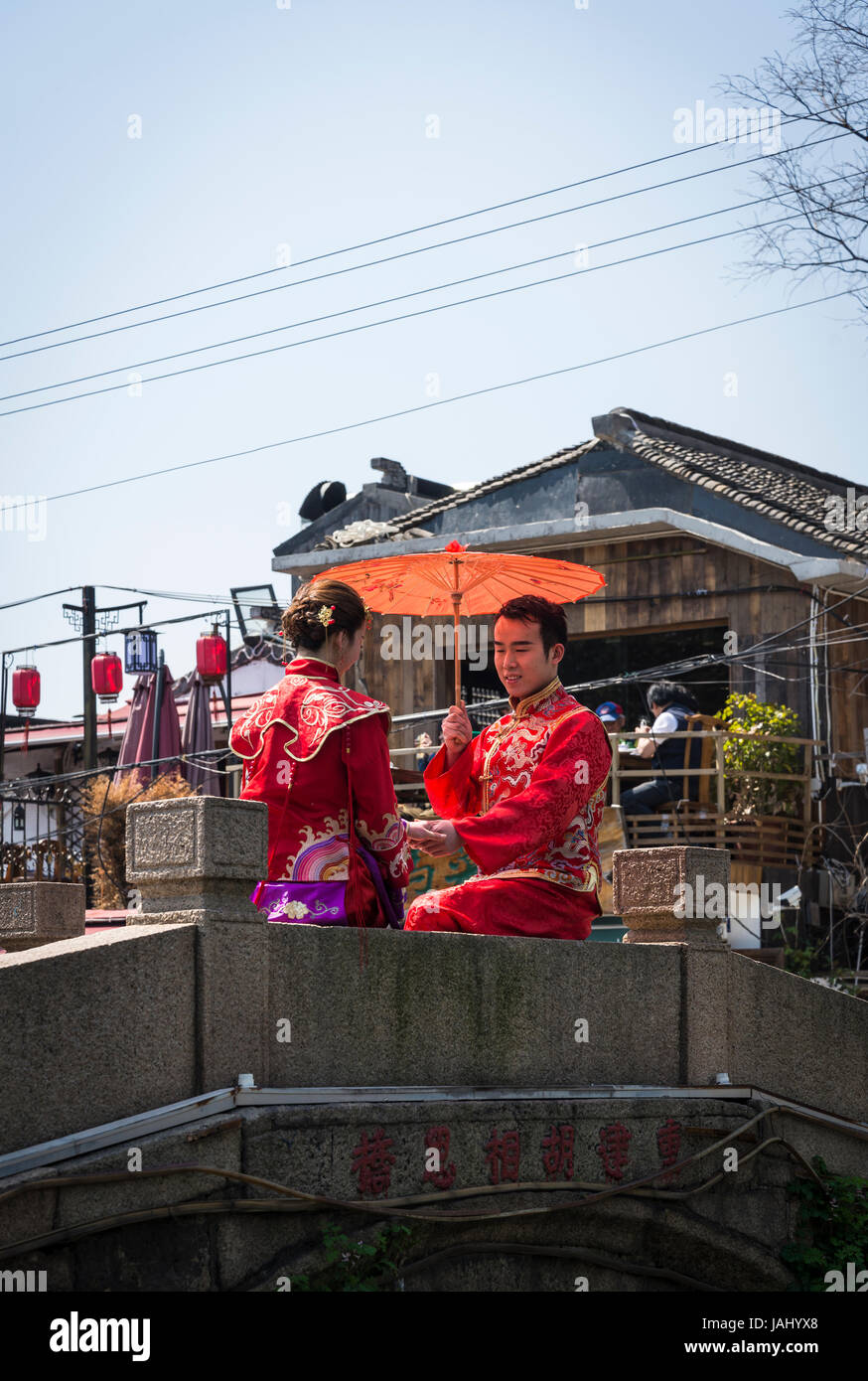 Young couple dressed in traditional clothes poses on a bridge ...